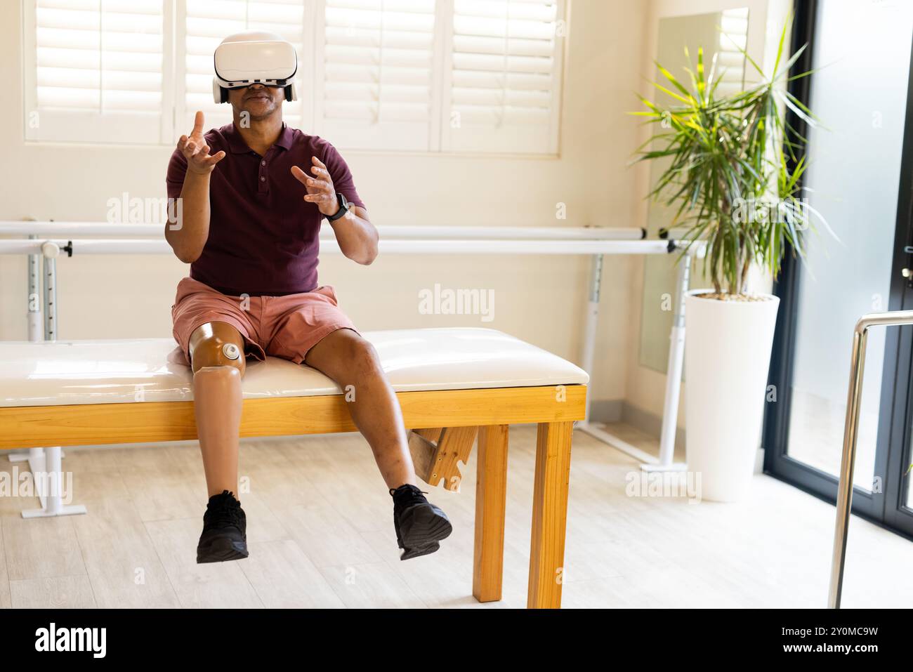 Using VR headset, man with prosthetic leg sitting on therapy table ...