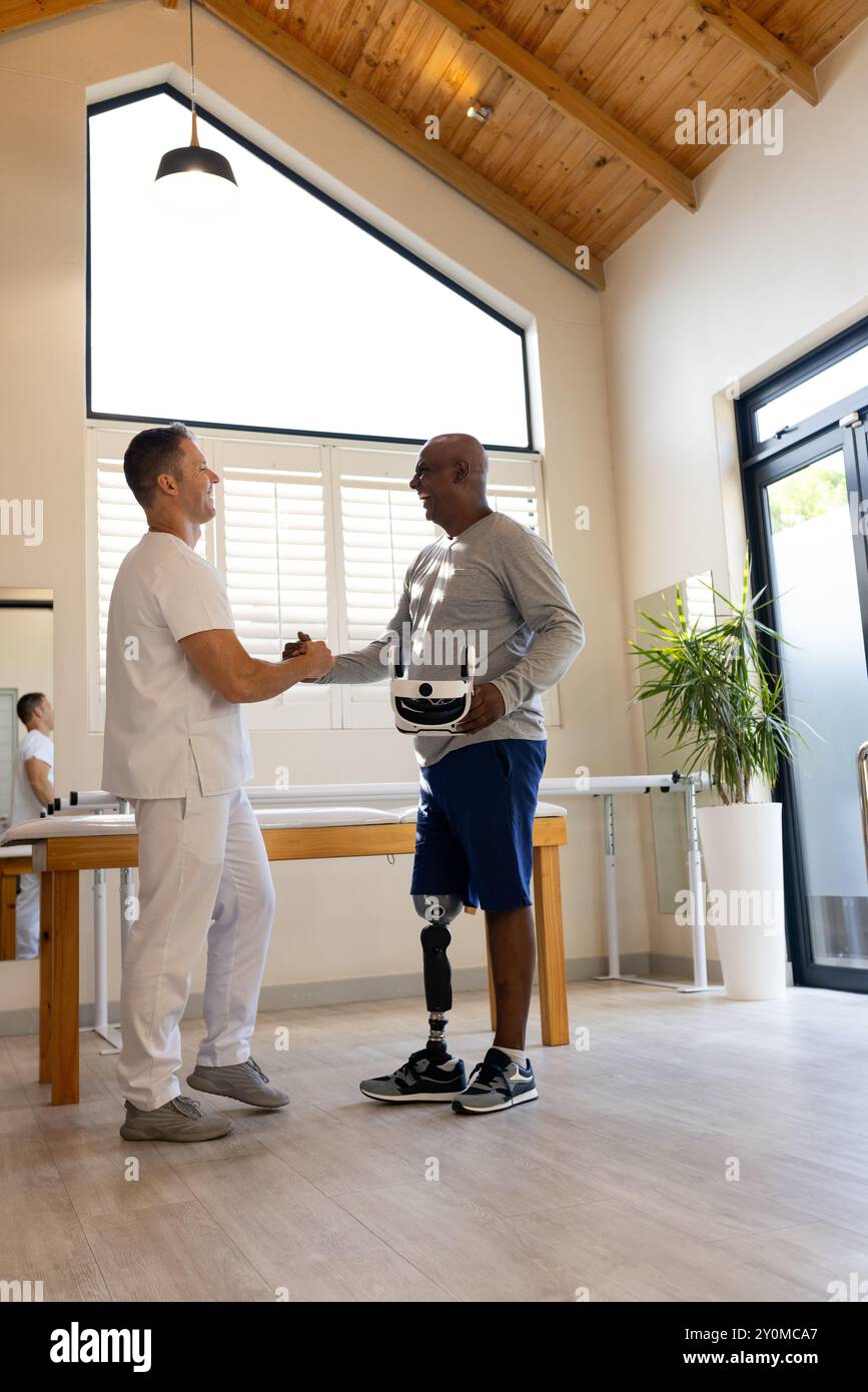 Man with prosthetic leg shaking hands with therapist in rehabilitation ...