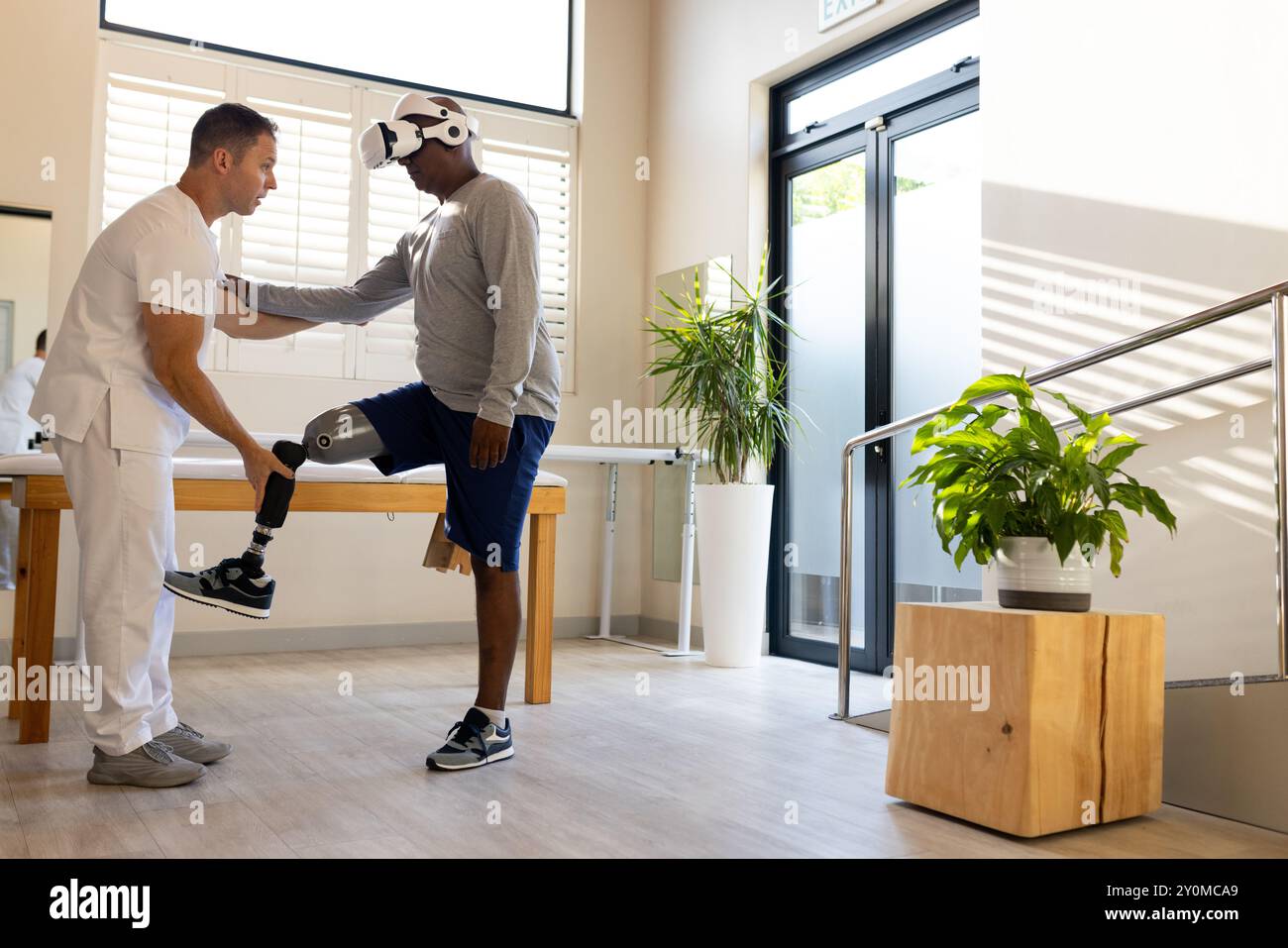 Therapist assisting man with prosthetic leg using VR headset in ...