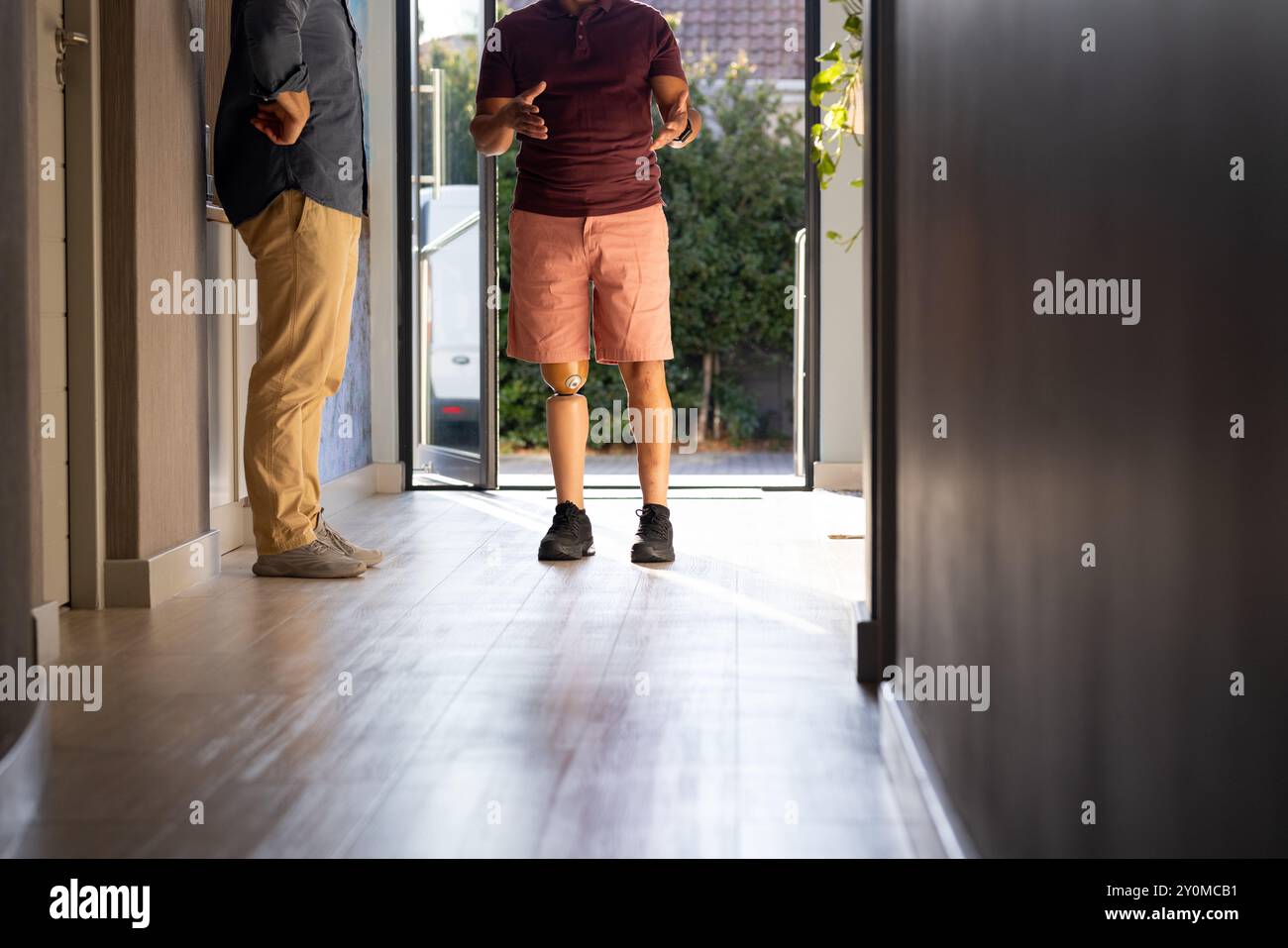 Man with prosthetic leg walking in hallway, discussing with another ...