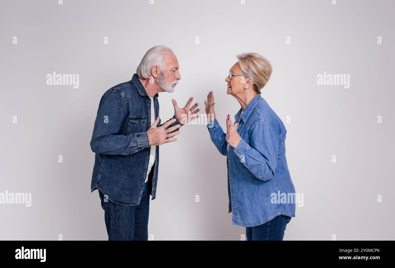 Side view of furious senior husband and wife blaming and fighting while ...