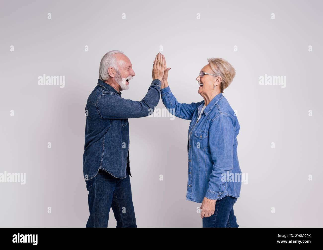 Side view of ecstatic senior couple giving high-five to each other and ...