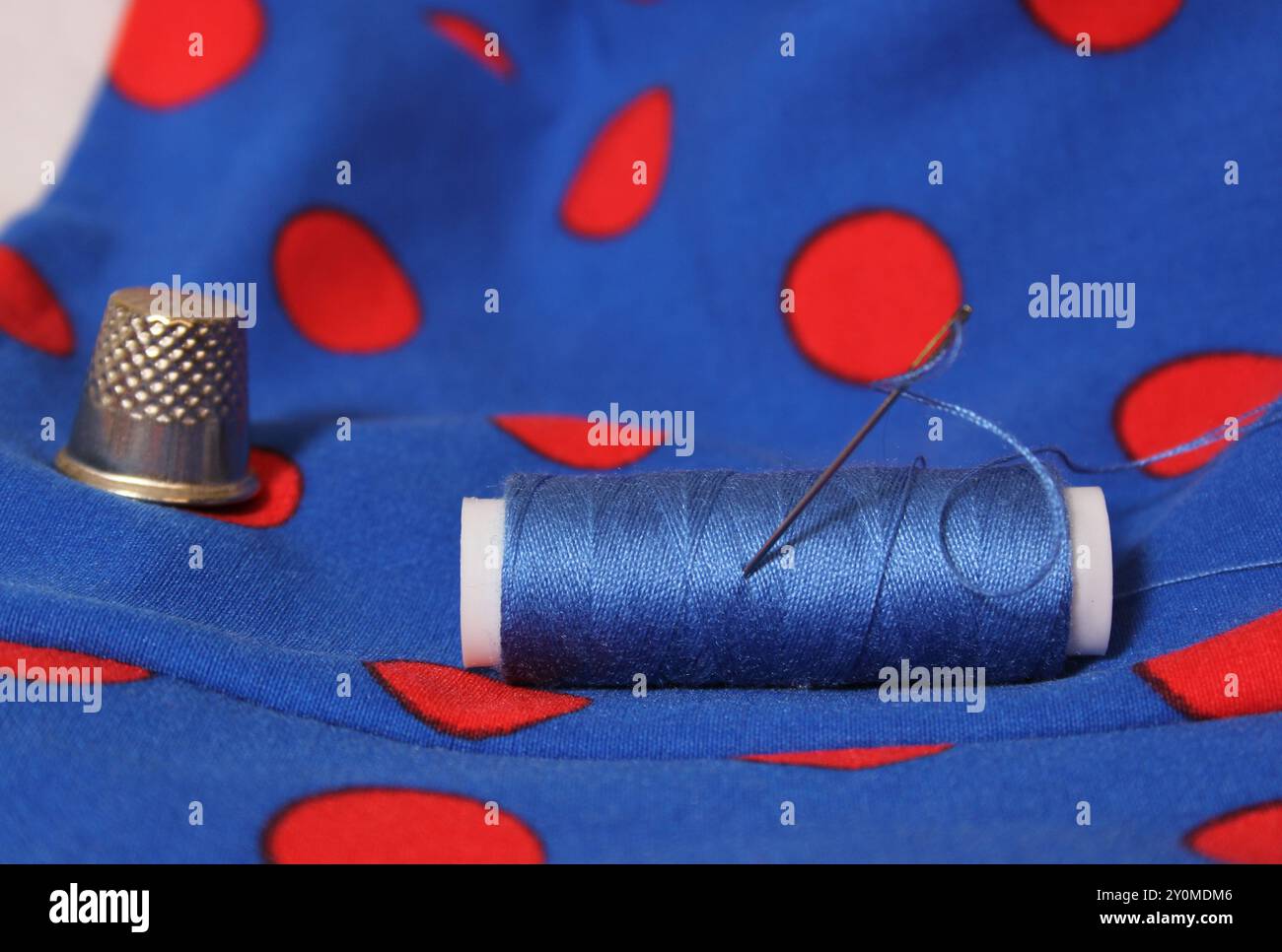 Spool of Blue Thread and Thimble on Vintage Blue and Red Dress Stock ...