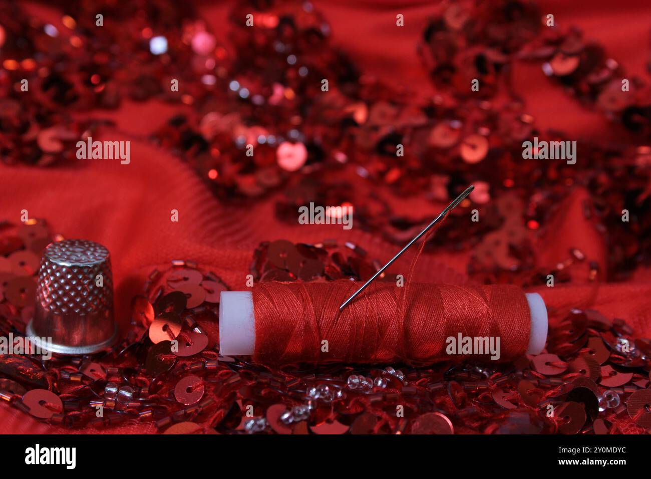Red Beaded Fabric With Spool of Red Thread and Thimble Stock Photo - Alamy