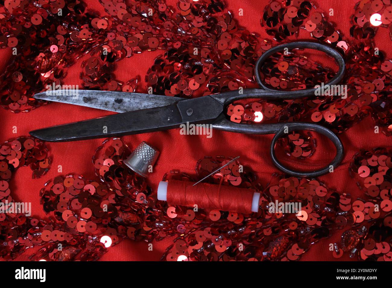Red Beaded Fabric With Spool of Red Thread and Thimble Stock Photo - Alamy