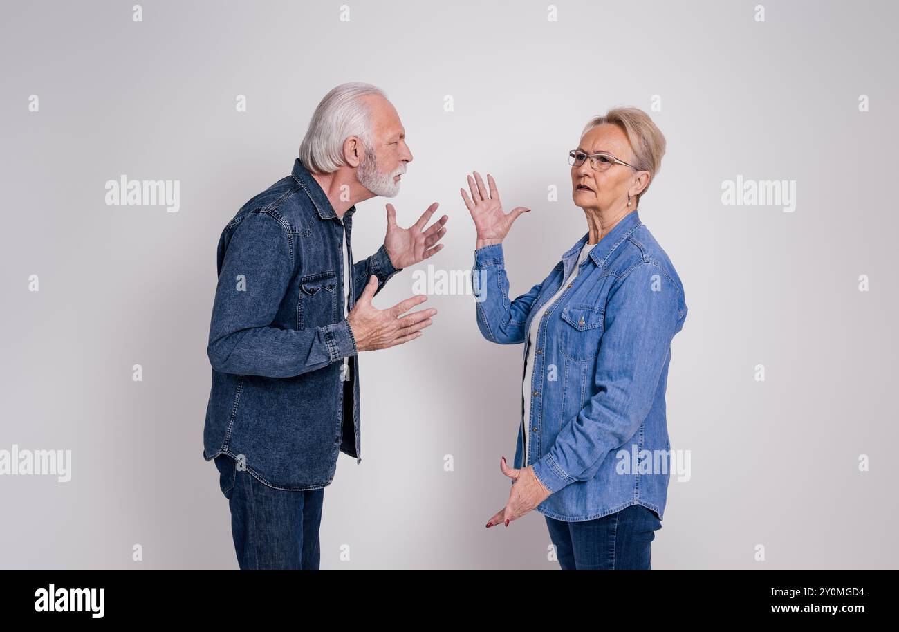 Frustrated senior wife looking away and ignoring angry husband arguing ...