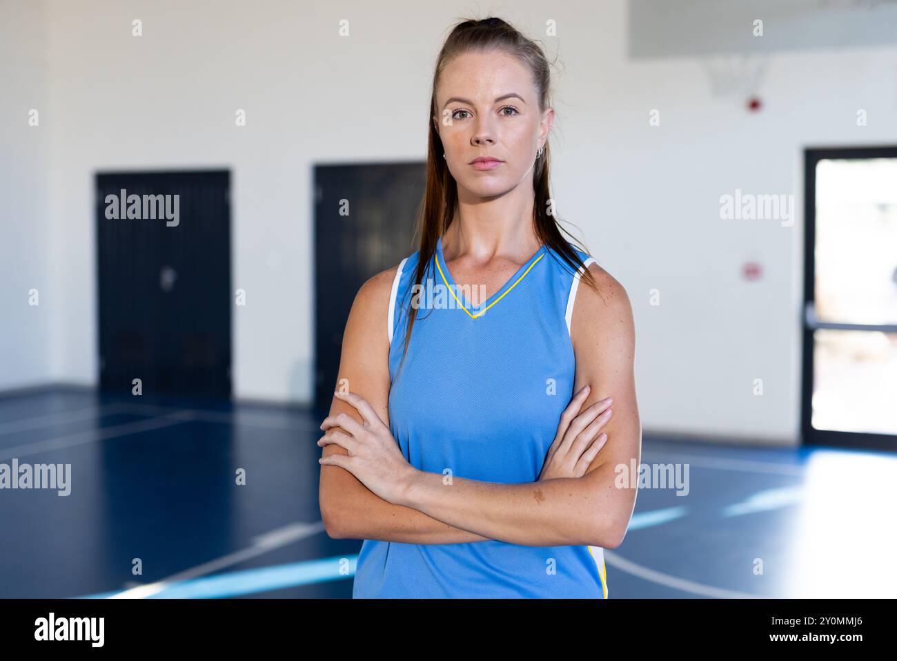 In gym, female basketball player standing with arms crossed, looking confident. Sports, athlete ...