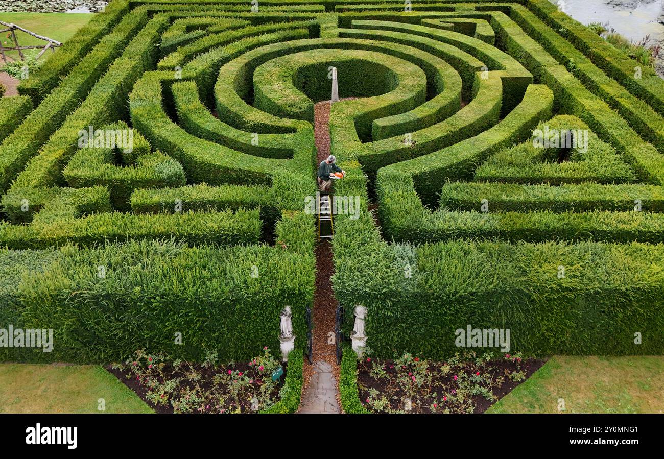 A gardener at Hever Castle tends to the bushes of the historic 120-year ...