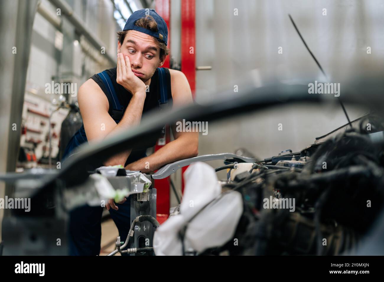Portrait of puzzled mechanic male with confused expression leaning on ...