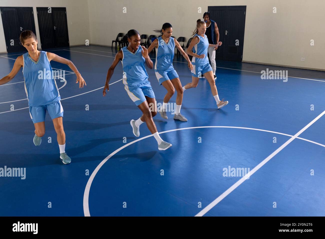 Female basketball team practicing drills on indoor court, focusing on ...