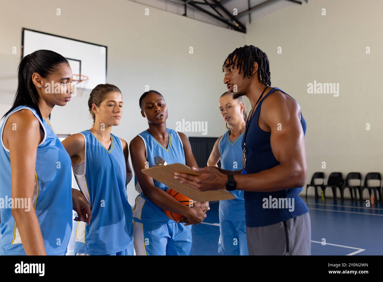 Basketball male coach discussing strategy with female team players in ...