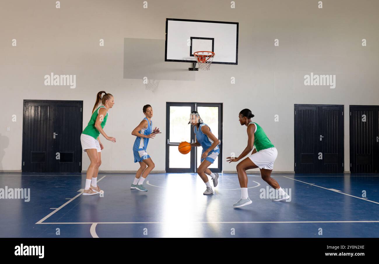 Playing basketball in school gym, female players competing in game ...