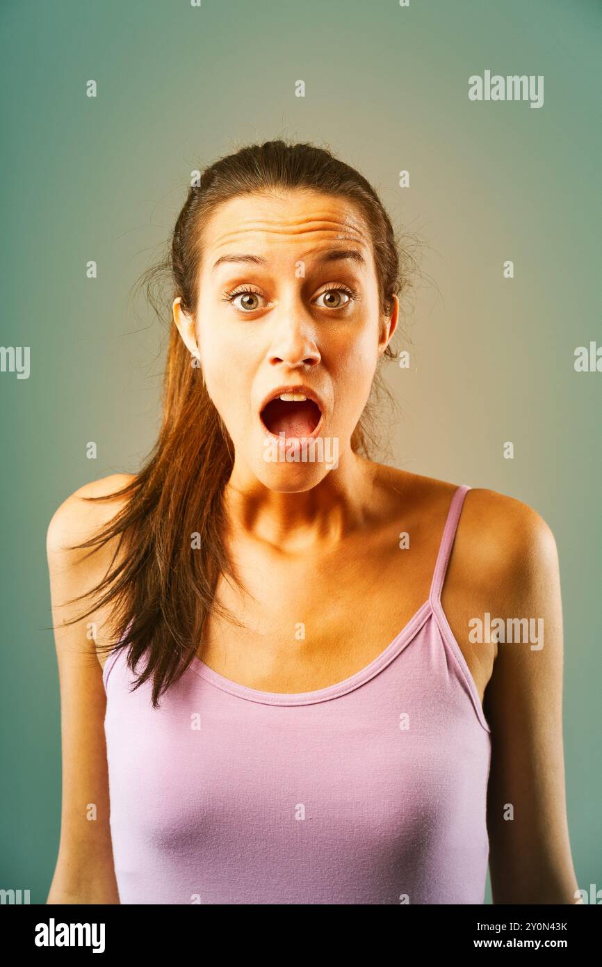 Young woman is gasping with her mouth wide open, raising her eyebrows ...