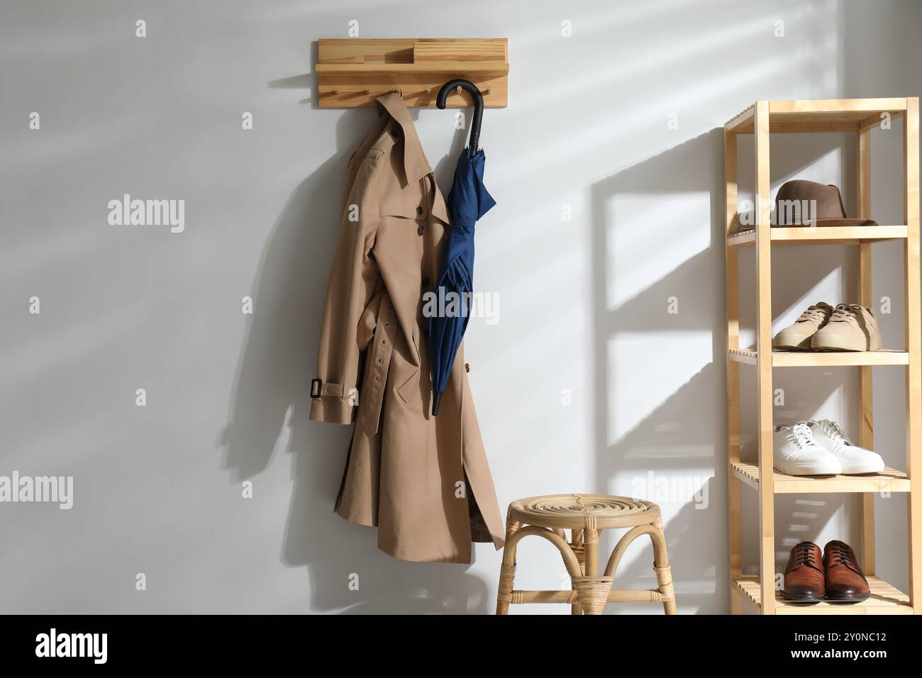 Colorful umbrella and trench coat hanging on rack at home Stock Photo ...
