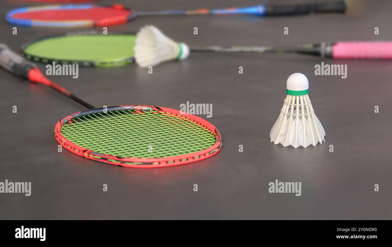 White badminton shuttlecocks and badminton rackets on dark background ...