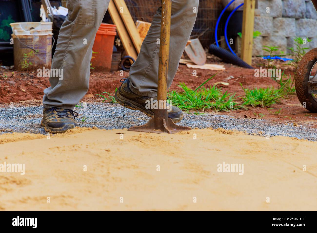 Worker uses manual rammer to tamp sand before constructing swimming ...