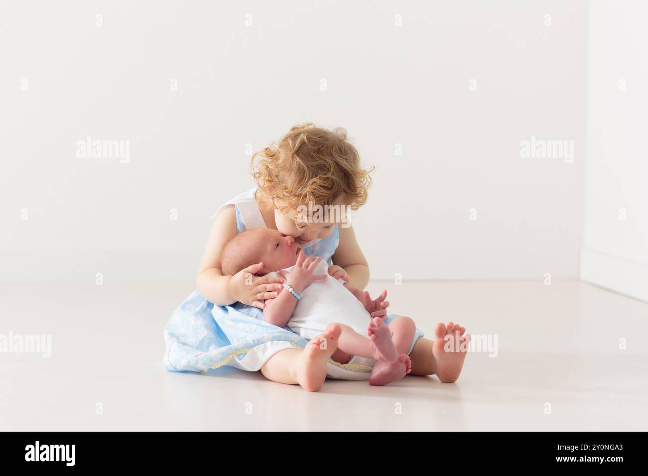 Siblings meet newborn baby. Child holding new infant brother for the ...