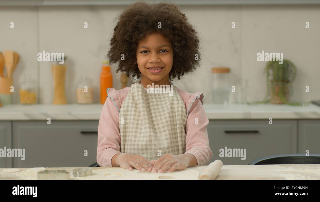 Portrait happy smiling little African American girl in apron alone ...