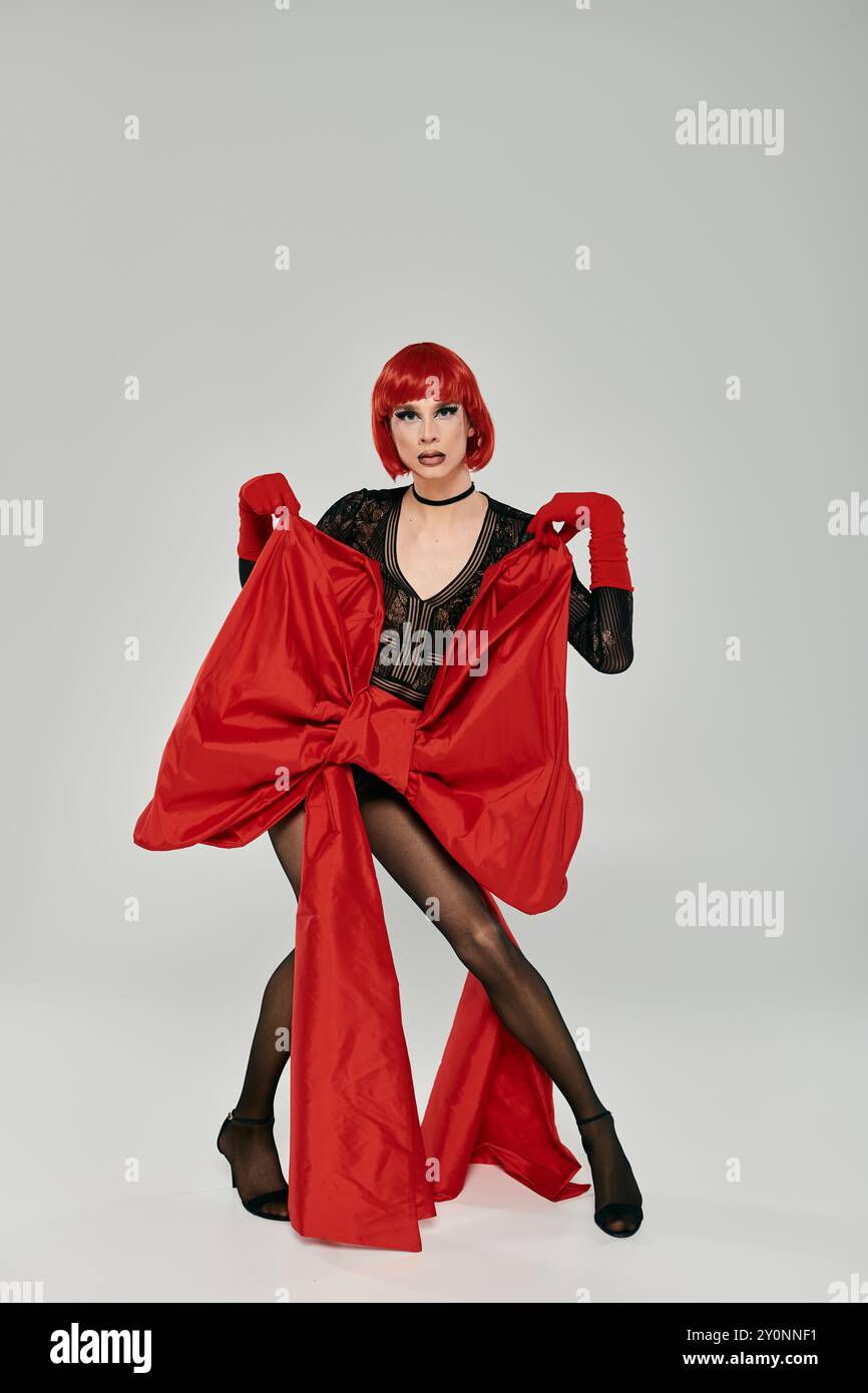 An attractive drag queen showcases a striking red outfit while posing ...