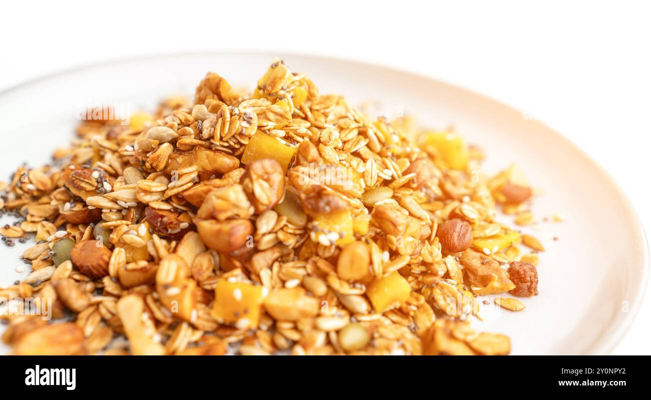 A bowl of granola with nuts and seeds on a white plate. The granola is ...