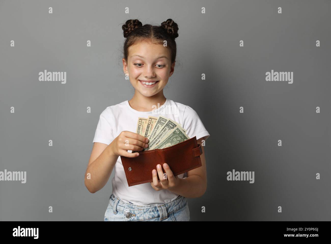 Pocket money. Cute girl with wallet and dollar banknotes on grey ...