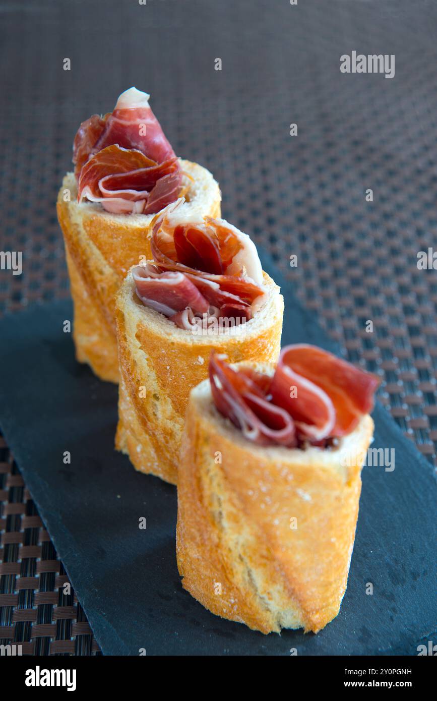Spanish tapa: rolls of bread stuffed with Iberian ham Stock Photo - Alamy