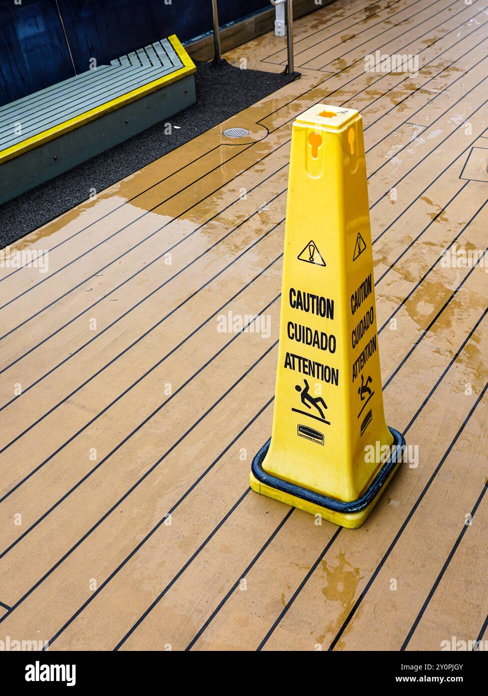 A yellow plastic warning pylon about the slippery wet floor on the deck ...