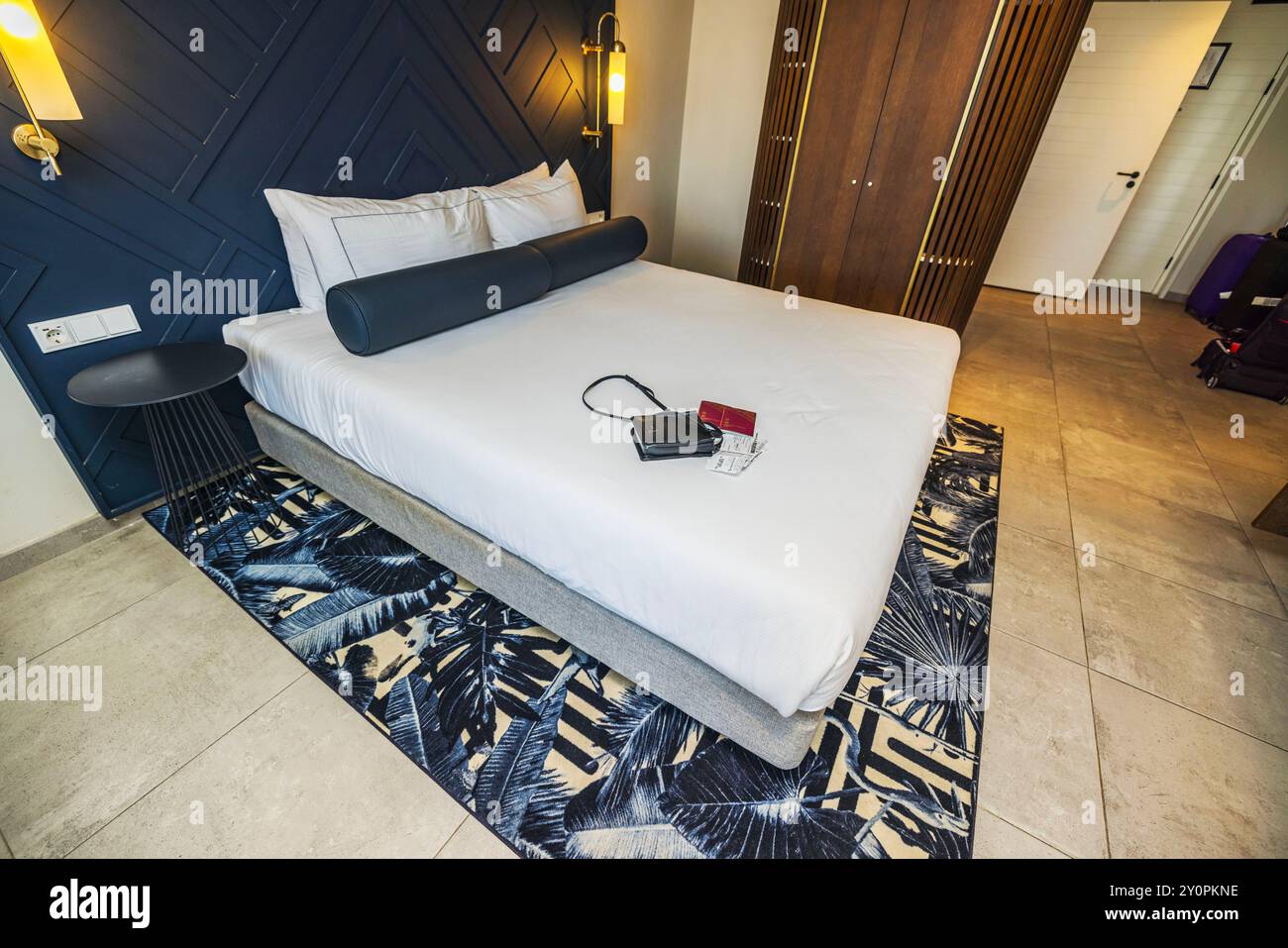 Modern hotel room with neatly made bed, featuring travel essentials ...