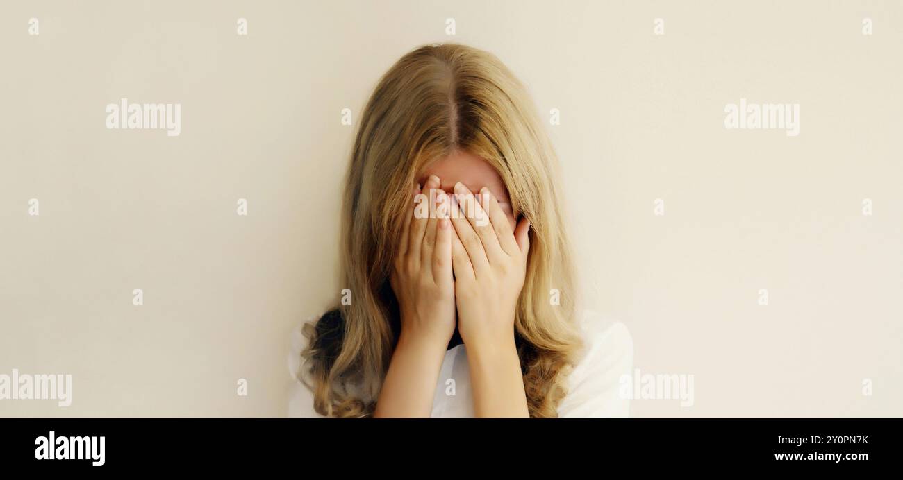 Upset sad crying woman covering her eyes and face with her hands while ...