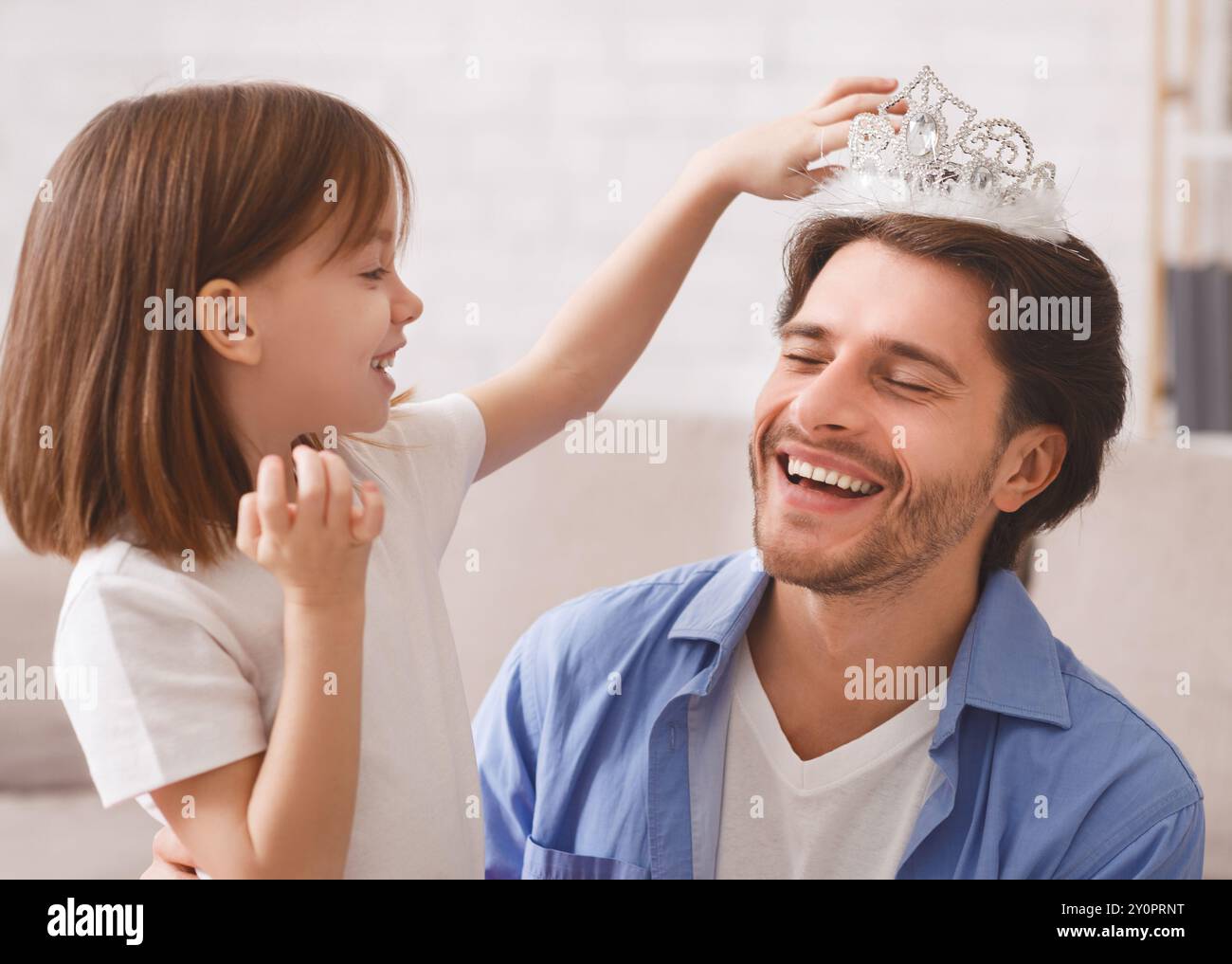 Little girl putting crown on her laughing father head Stock Photo - Alamy