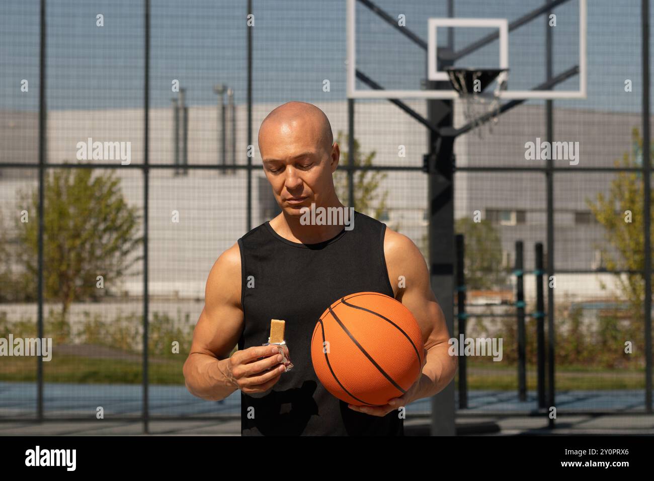 Sports man or basketball player eating energy bar. Muscular athlete ...
