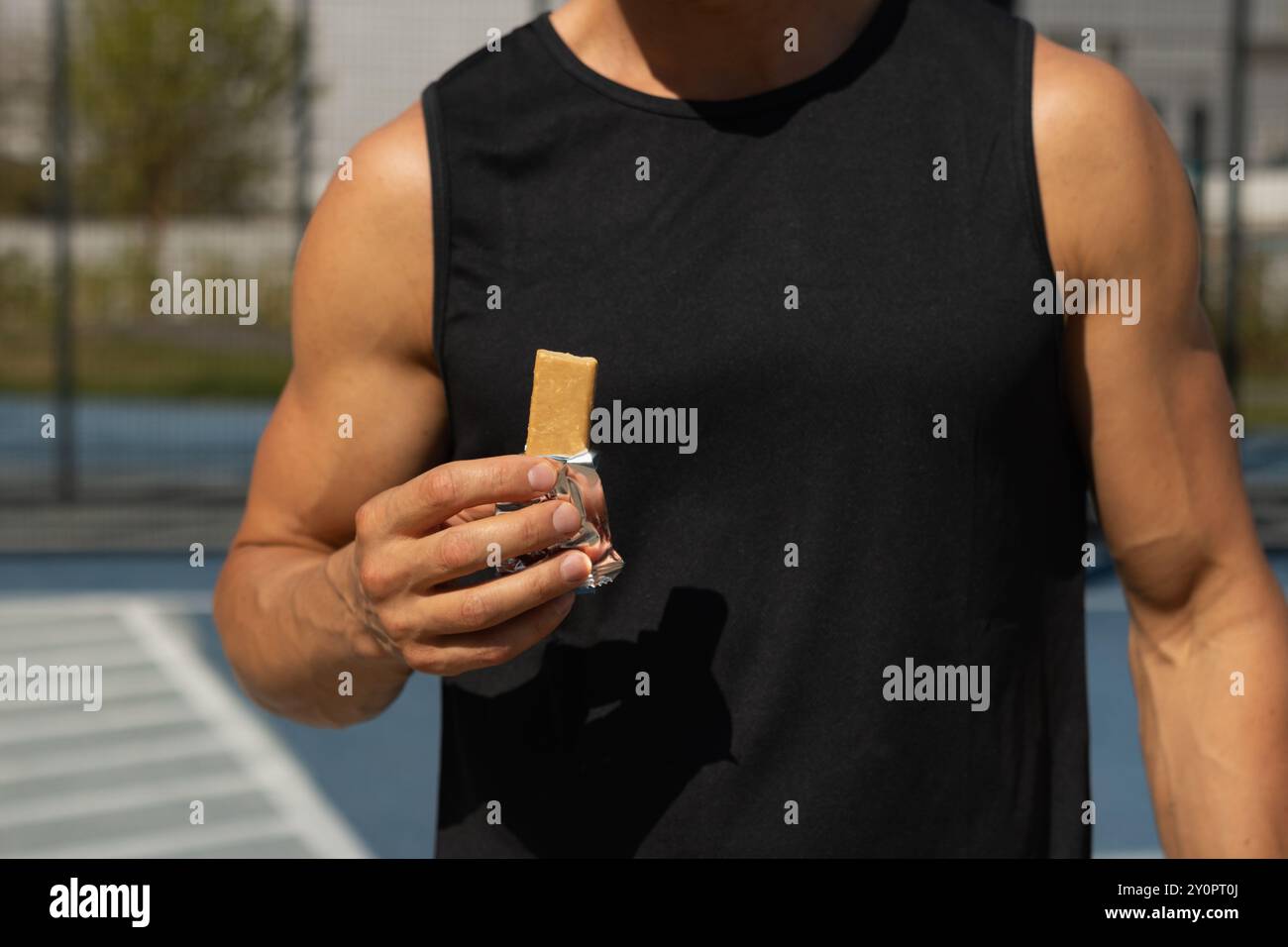 Sports man eating energy bar. Muscular athlete snacks on protein bar ...