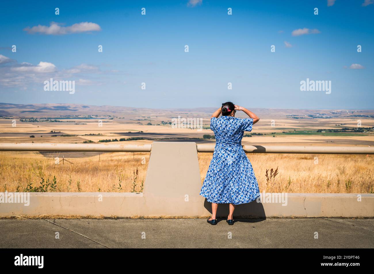 A woman looks out over the Oregon prairie and farm land from a highway ...