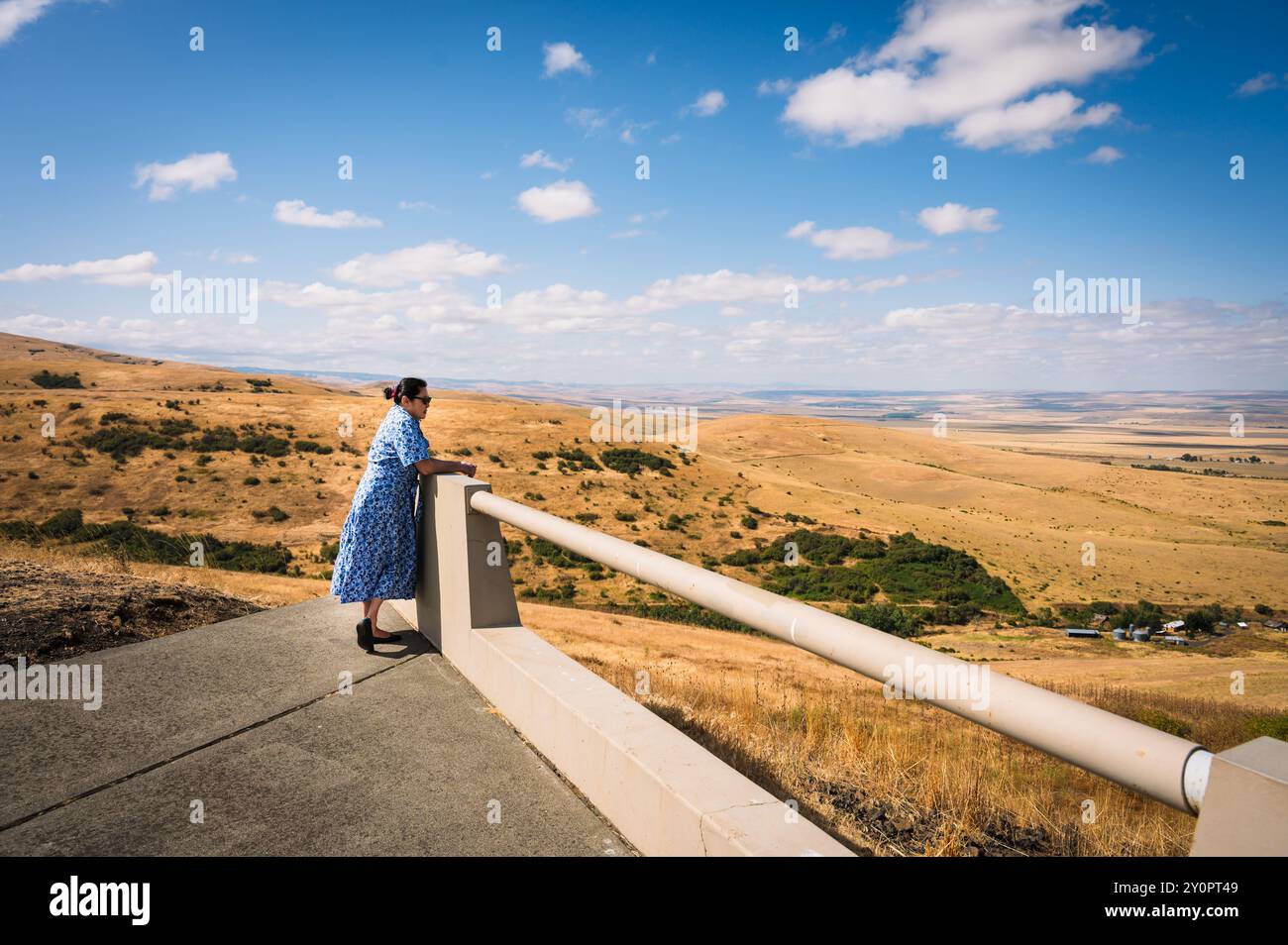 A woman looks out over the Oregon prairie and farm land from a highway ...