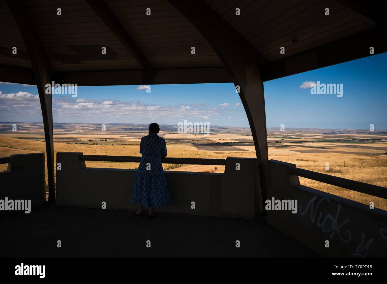 A woman looks out over the Oregon prairie and farm land from a highway ...