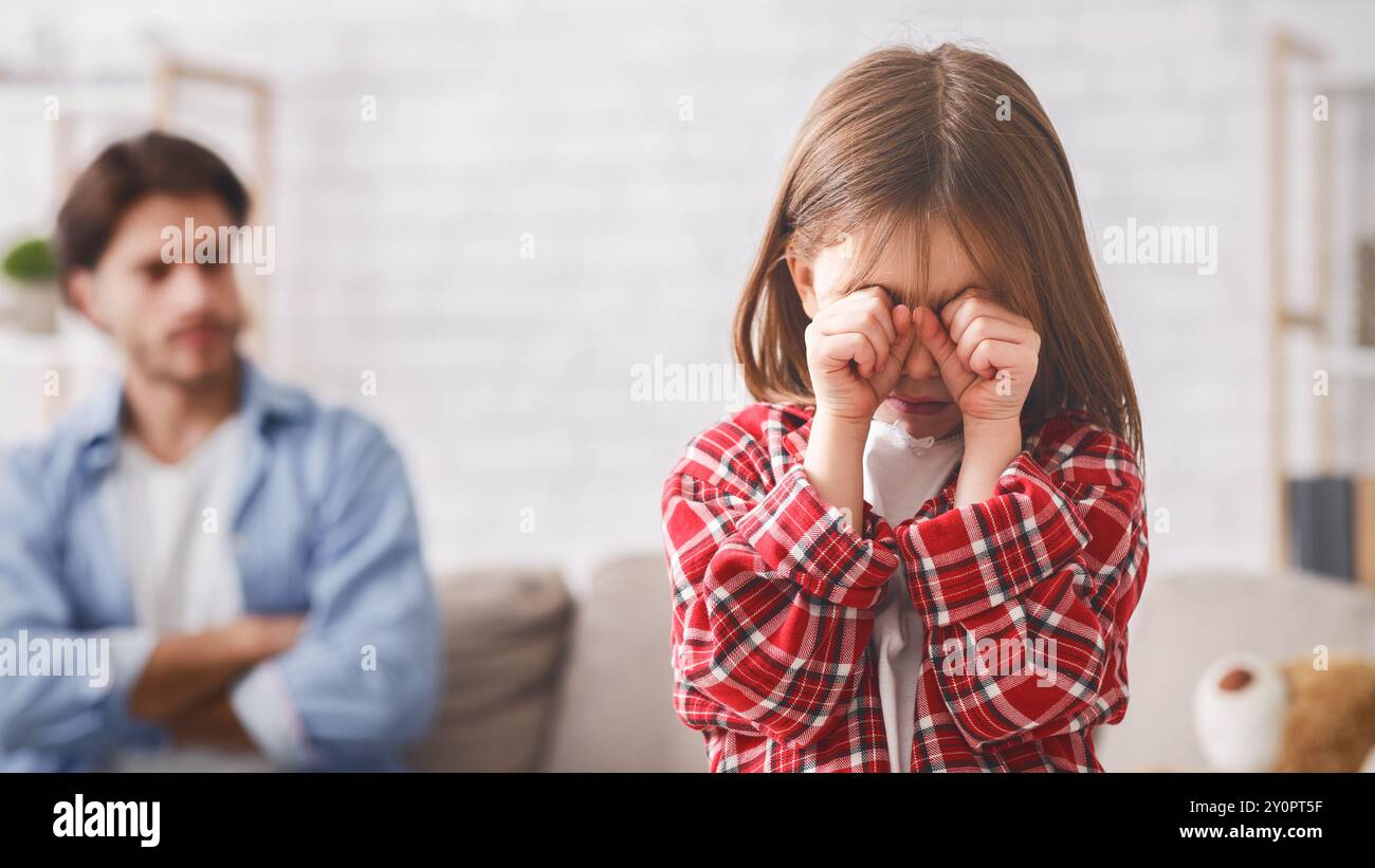 Little girl crying after quarrel wIth father, angry dad behind Stock ...