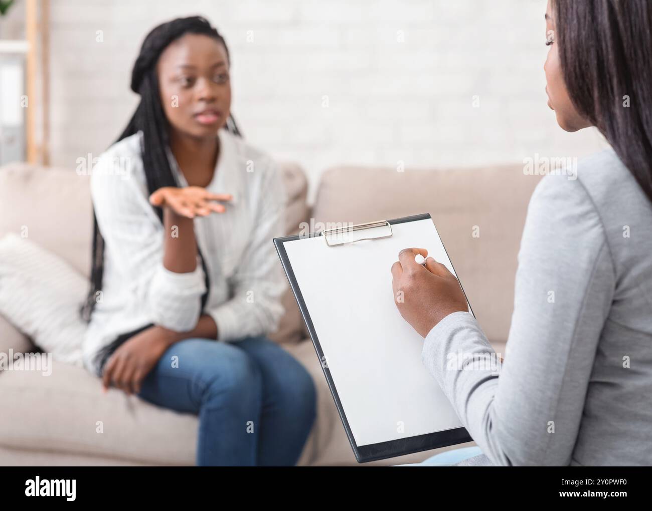 Psychologist taking notes during therapy session with her emotional ...