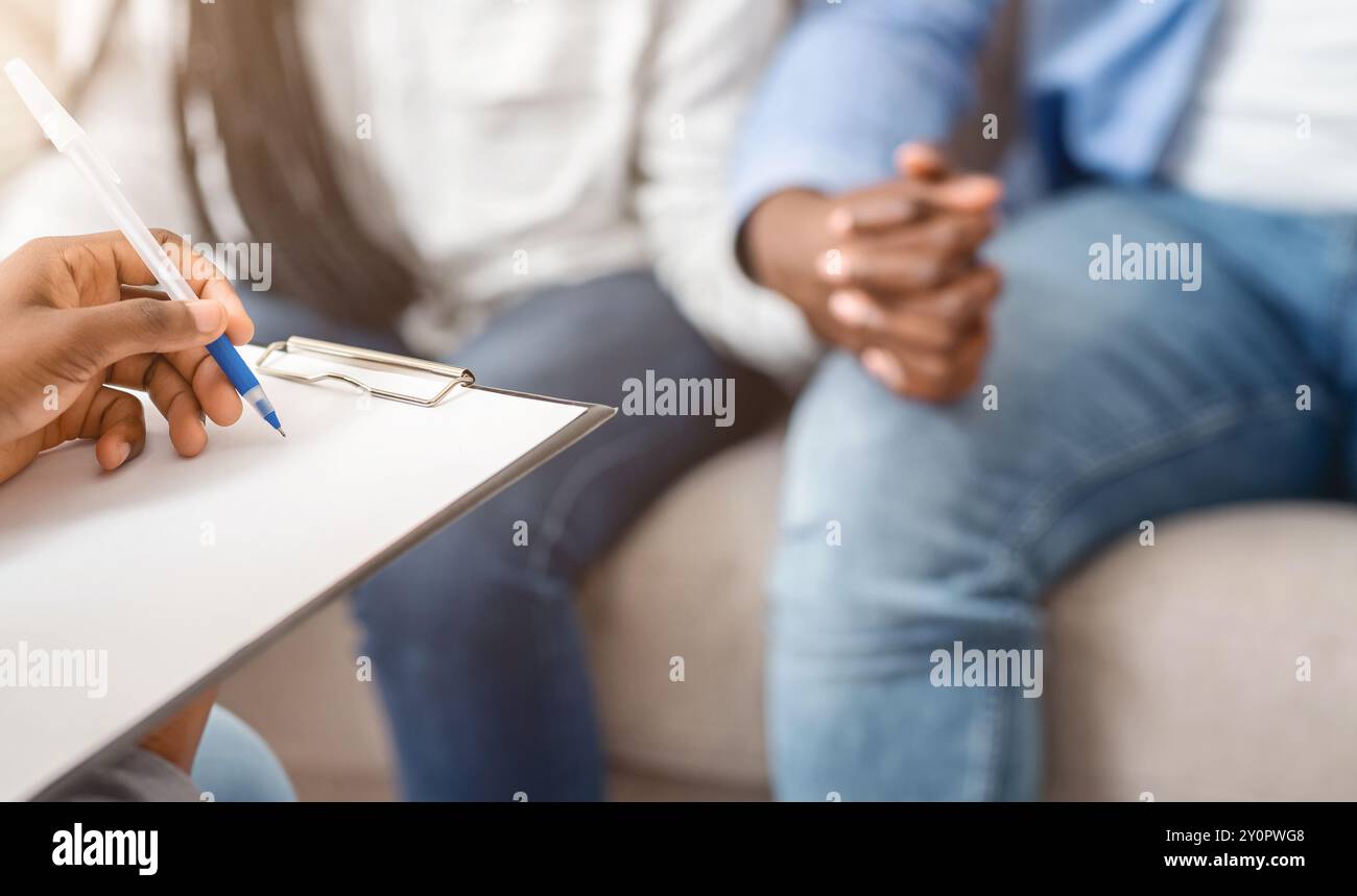 Marriage counselor taking notes during therapy session with black ...