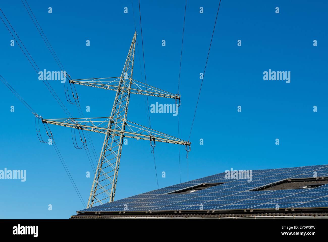 Solar panels on a rooftop with a high voltage transmission tower and ...
