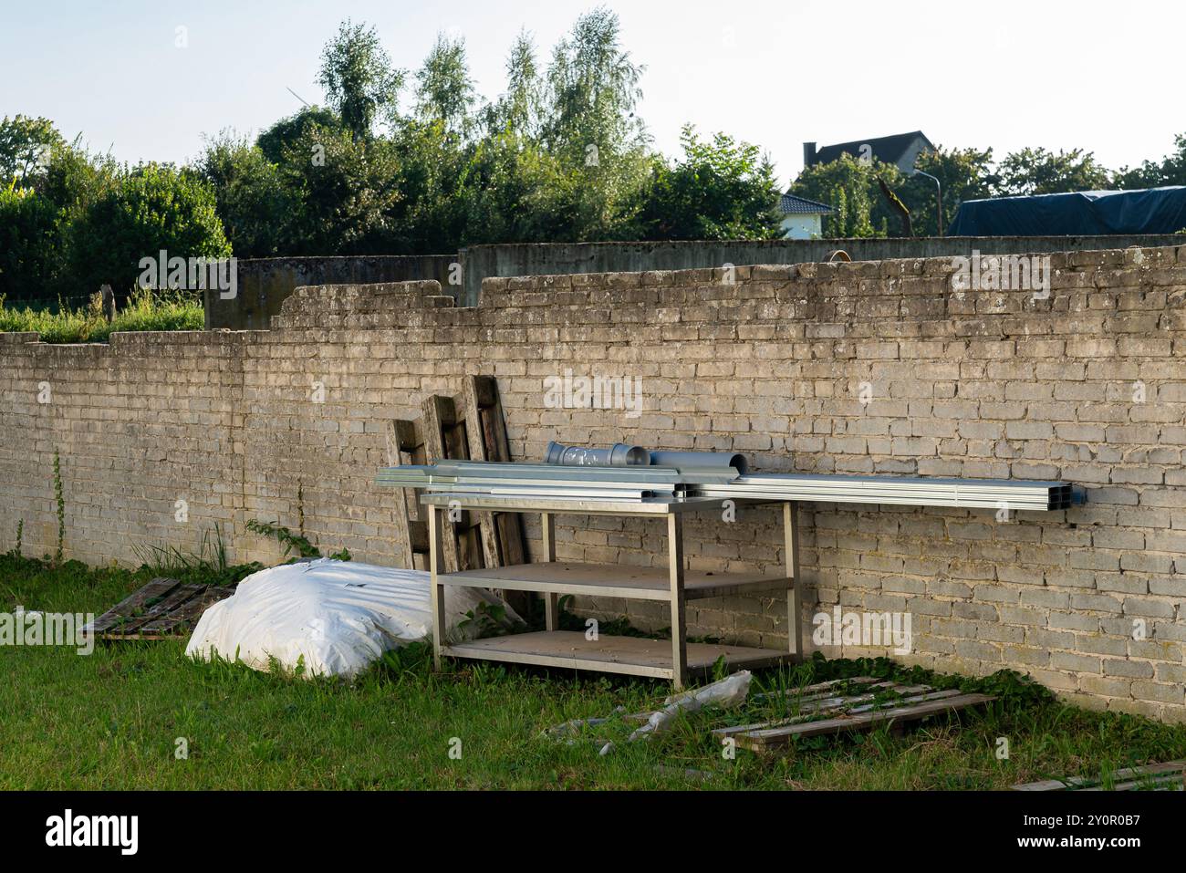A workbench holds construction materials stacked beside a brick wall in ...