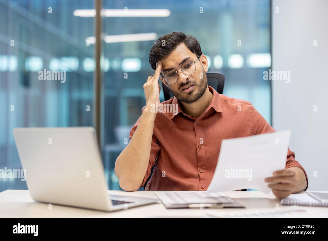 Businessman feeling stressed while reviewing documents at office desk ...