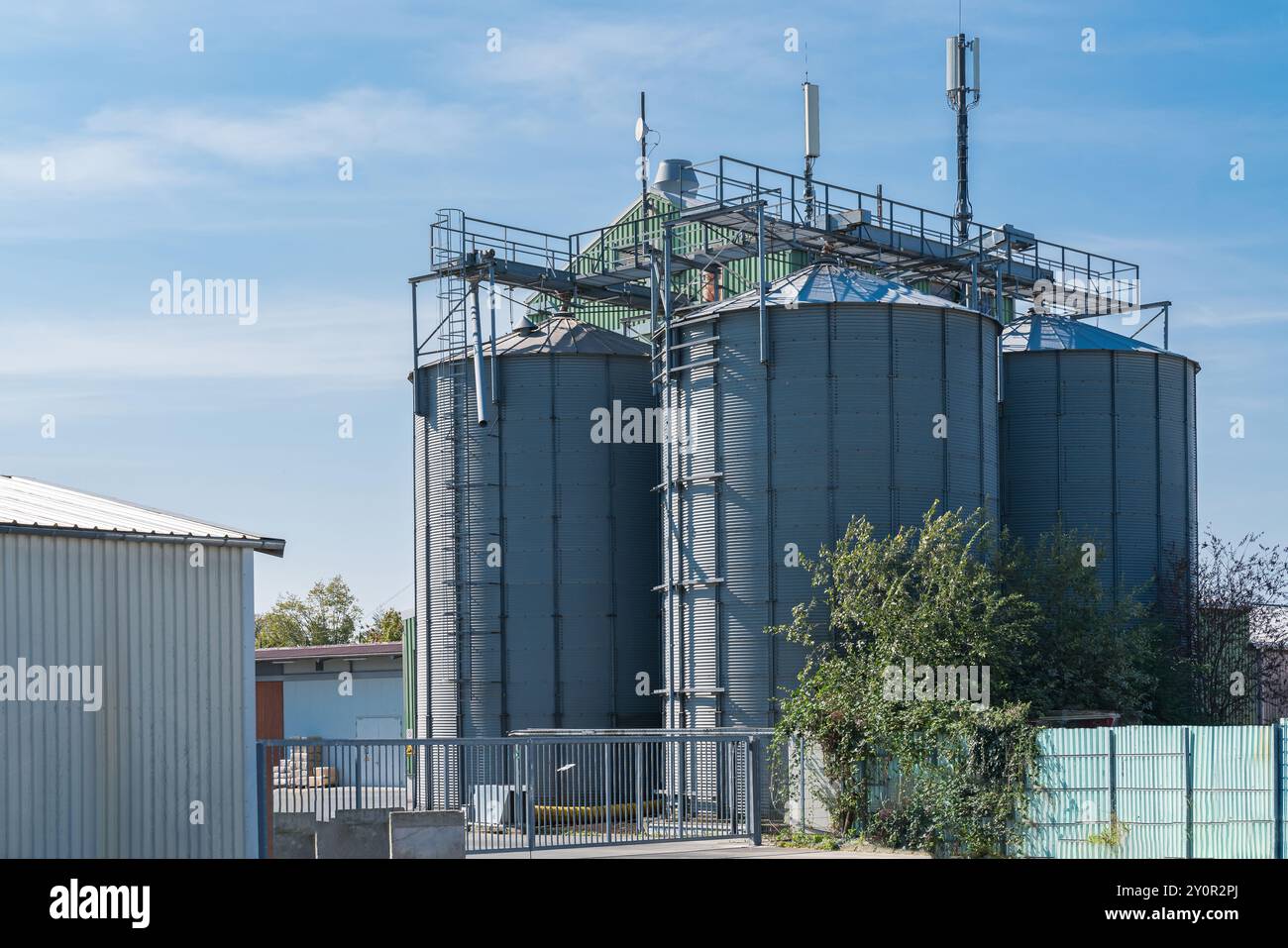 Three large silos stand prominently next to an industrial storage ...