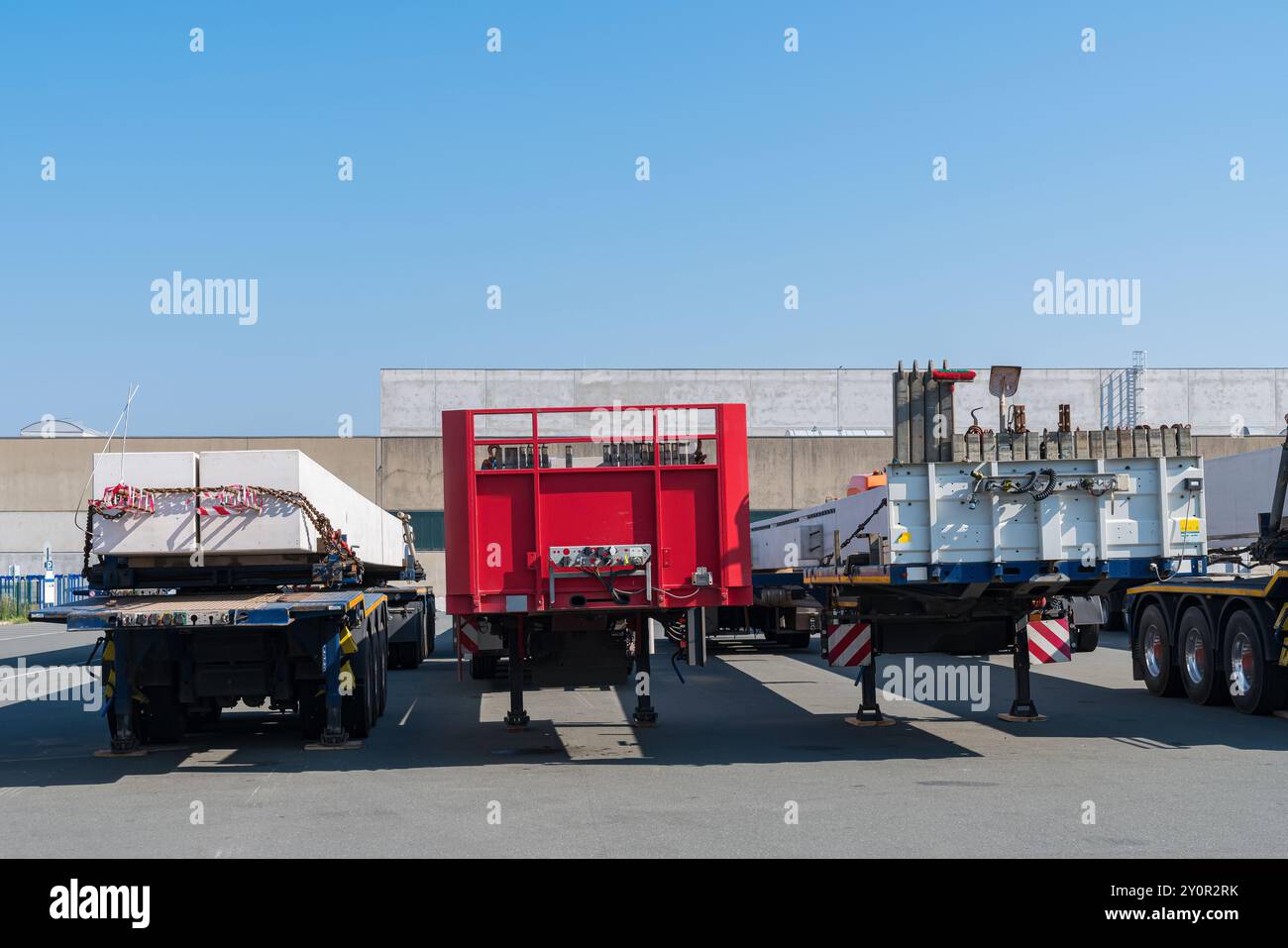 Rear view of long car trailers with reinforced concrete beams standing ...