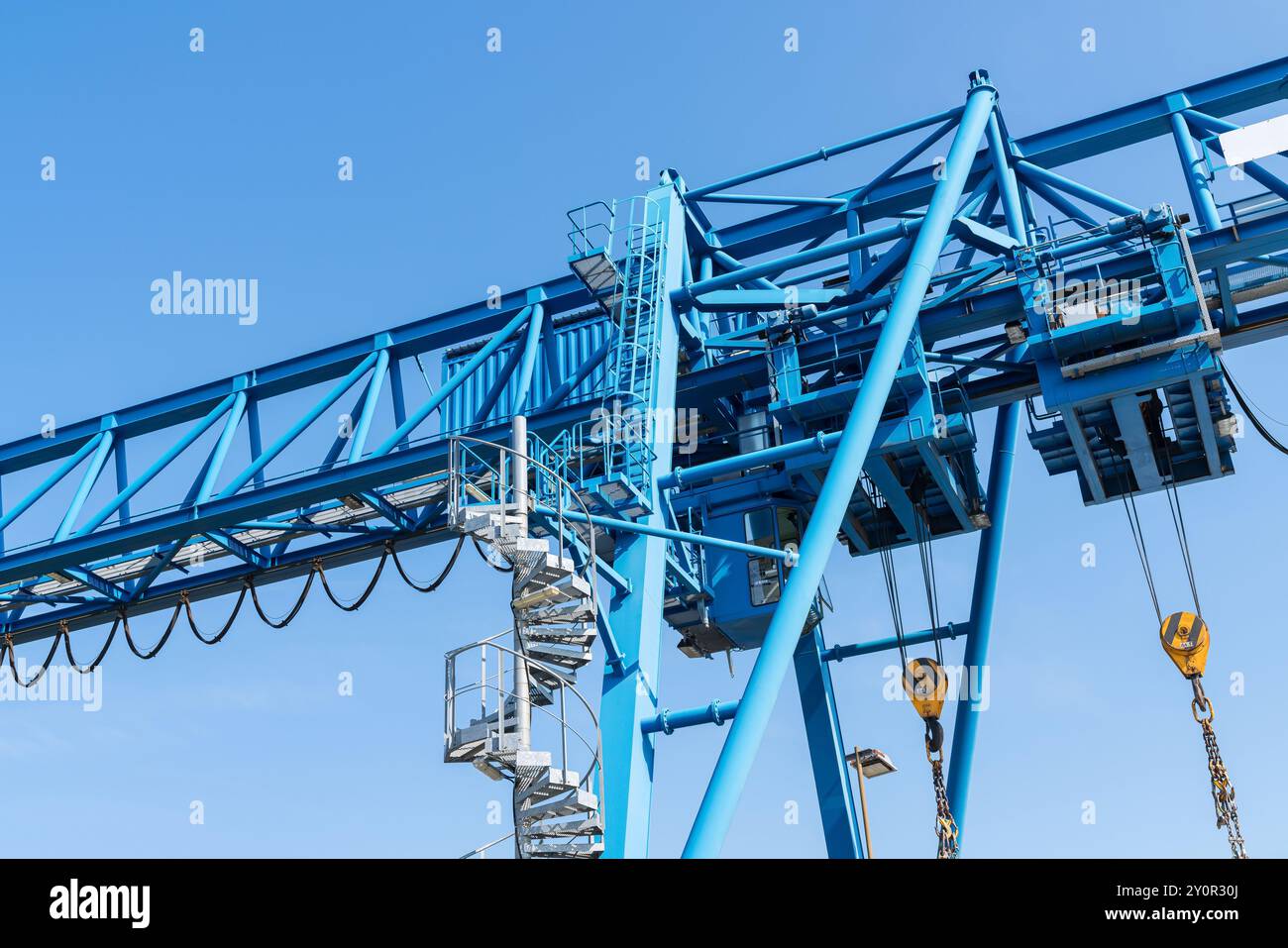Driver's cabin and part of an overhead crane against a blue sky. Close ...