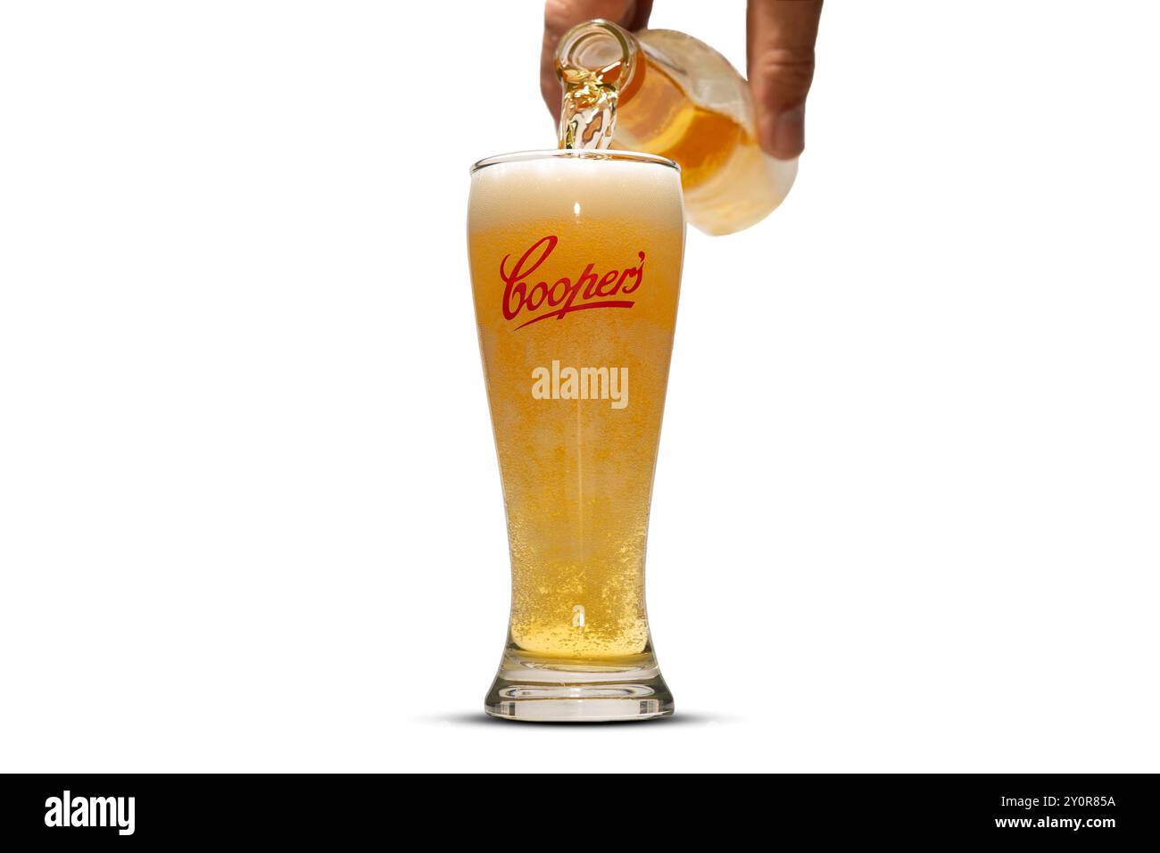 Cold Cooper's lager beer pour into a tall glass with a foamy head on a ...