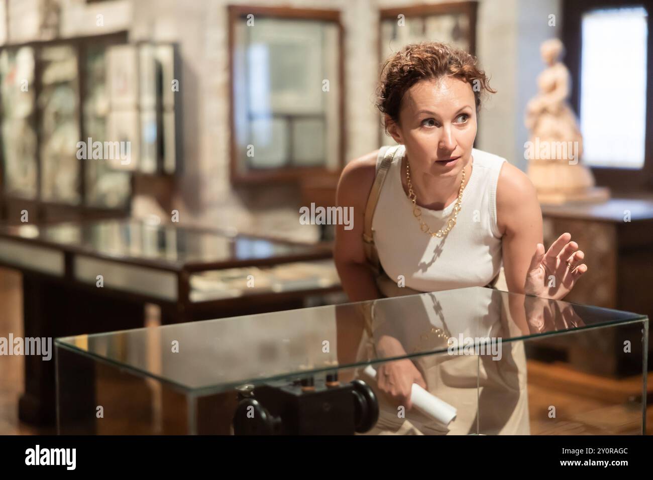Woman with sheet piece of paper in her hands walks around museum hall ...