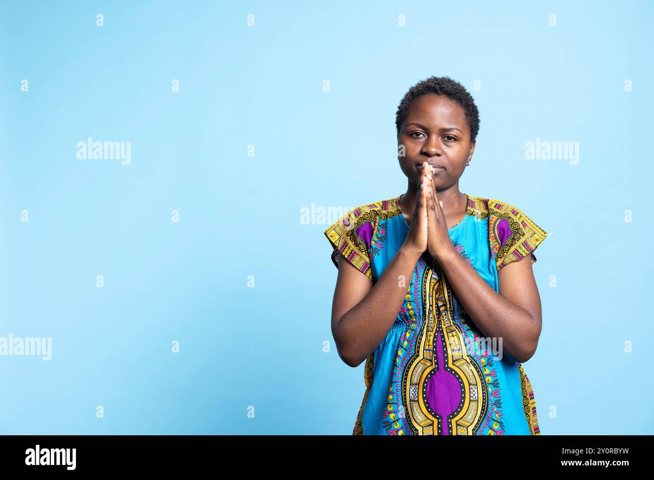 Optimistic pious girl holding hands in a prayer to talk to Lord, saying ...