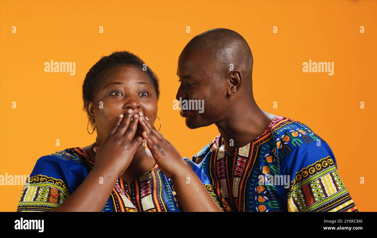 Cheerful man sharing important secret with his wife, whispering in her ...