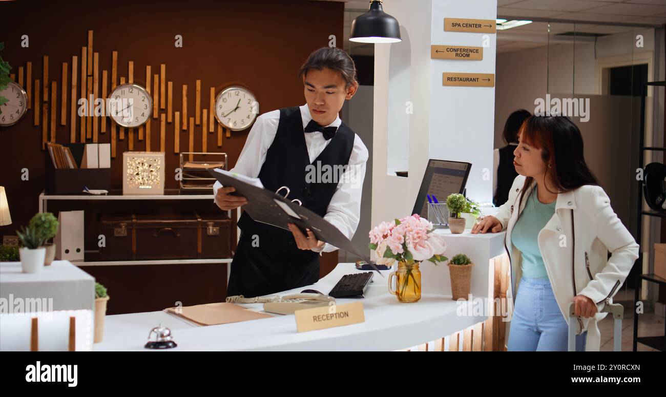 Asian client asking hotel concierge about accommodation, arriving at reception front desk. Staff ...
