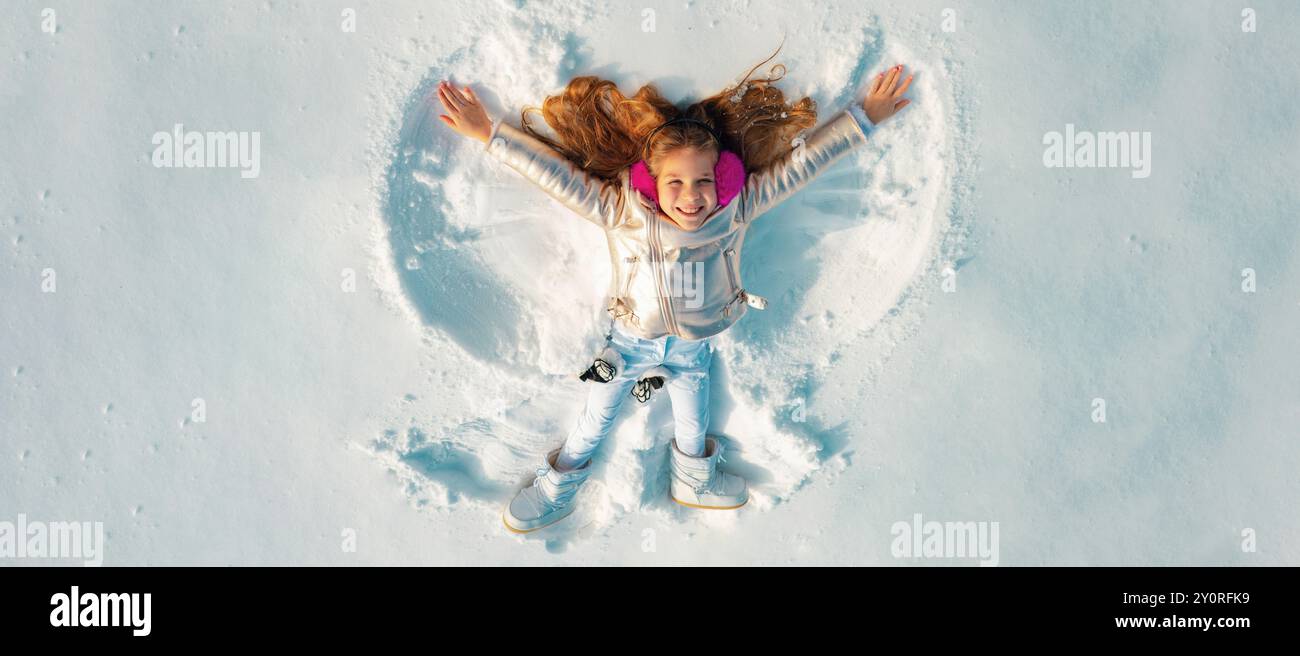 Snow angel. Smiling child lying on snow with copy space. Funny kid ...